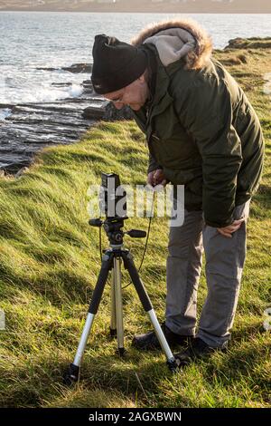 A older man photographing with an old film camera in the city with ...