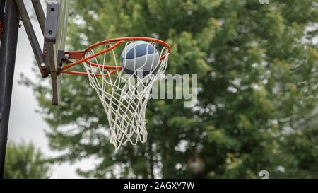 Street basketball ball falling into the hoop at night. Urban youth game ...