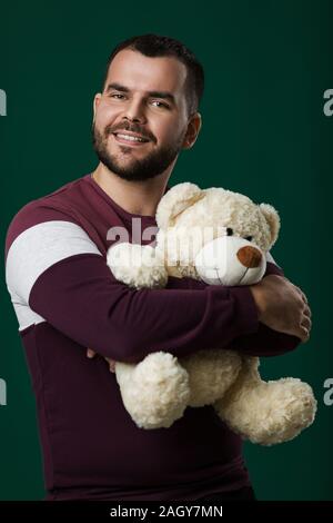 bearded smiling man holding teddy bear, isolated on blue Stock Photo ...