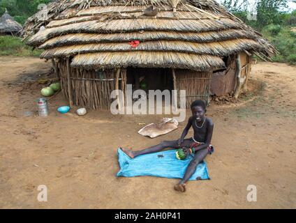 Larim tribe girl cutting a vegetable in front of her house, Boya ...