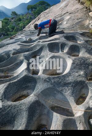 Lotuko tribe woman grinding grains in a hole in the rock, Central ...