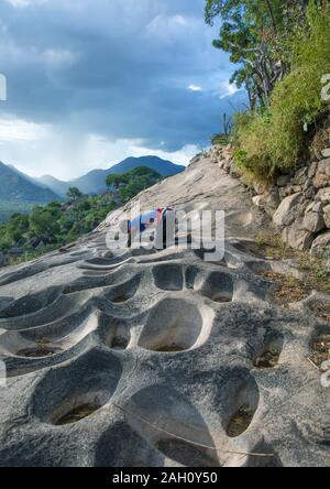 Lotuko tribe woman grinding grains in a hole in the rock, Central ...