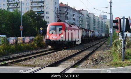 Red electric locomotive in OBB livery, with passenger train at a ...