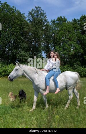 Portrait of two best friends riding together on a horse Stock Photo - Alamy