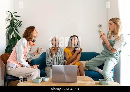Four women sitting on couch talking Stock Photo - Alamy