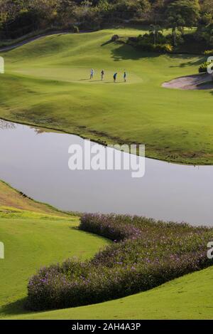 Golf course with a pond in the background. The pond is surrounded by ...