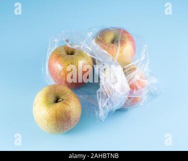 White plastic sachet packet with apples on wood table. Mock-up template ...
