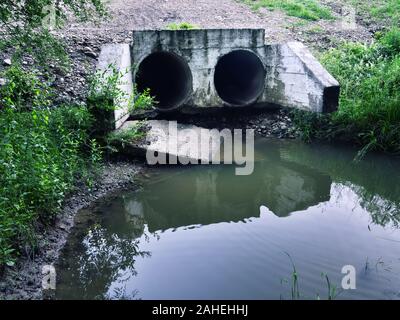 Drainage system under the highway. Concrete pipe under the road. River ...