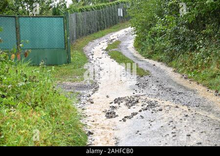 Rainwater washes out a dirt road and destroys asphalt after a summer ...