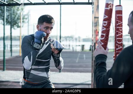 Confident sportsman looking at the boxing stick during MMA training ...