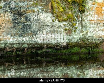a landscape with a steep river and caves on a sandstone cliff, a cloudy ...