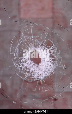 Broken glass. Round hole with radial cracks in the glass. Round white ...