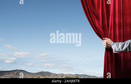 Human hand opens red curtain on natural landscape background Stock ...