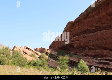Red rock formations jutting out of the ground surrounded by shrubs ...