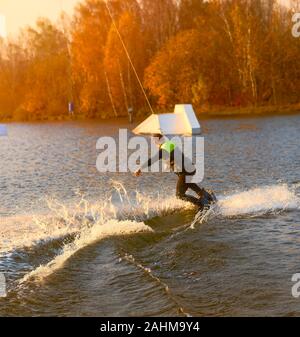 Wakeboarder making tricks. Low angle shot of man wakeboarding on a lake ...