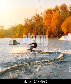 Wakeboarder making tricks. Low angle shot of man wakeboarding on a lake ...