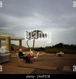 Two couples at dinner on a patio make a toast, back view Stock Photo ...