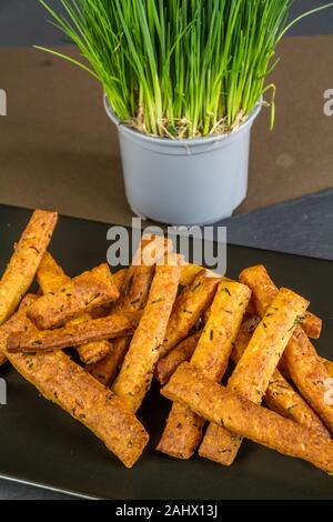 Plate of stacked cheese straws with chive plant behind, portrait Stock ...