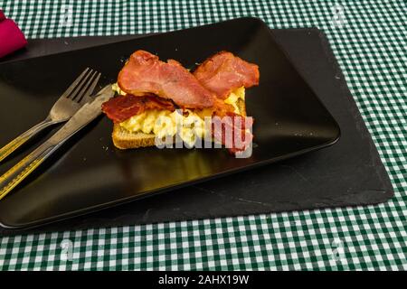Elevated view of Rashers of bacon and scrambled egg on toasted brown ...