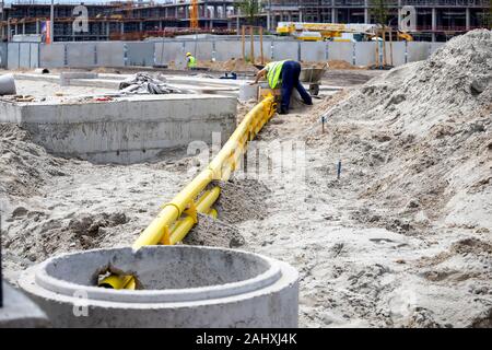 Trench with yellow ducts for cable. Laying of underground cables ...