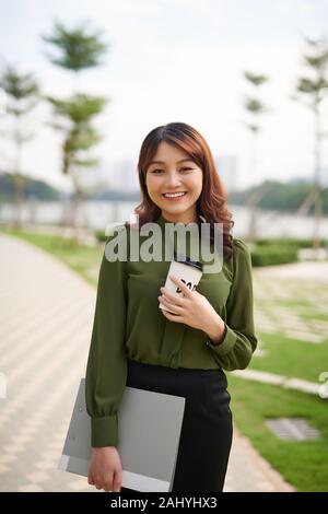 Pretty Vietnamese business woman reading information on tablet computer ...