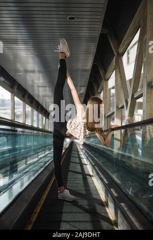 Ballerina lifting leg high in dramatic extension while partner holds ...