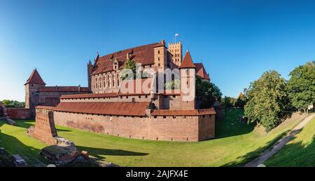 Red brick Malbork Castle in northern Poland shows keep, flags, and ...