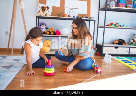 Beautiful teacher and toddler building pyramid using hoops around lots ...