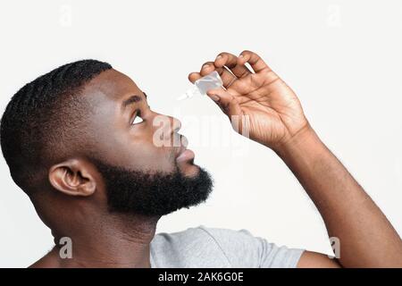 Black guy applying ophthalmology eyedropper. Glaucoma eye prevention ...
