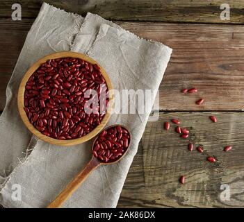 raw oval red beans in a plate on a wooden table. Organic meal ...
