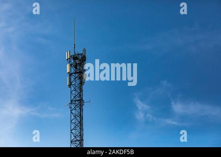 5G telecommunications tower and single cellular provider mast framed by ...