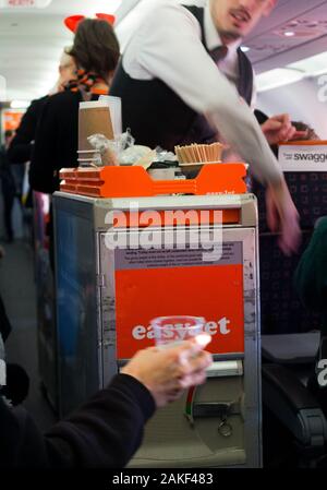 Cabin crew / air steward serves drinks and snacks to passengers ...
