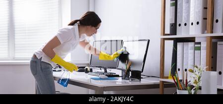 Young Woman Cleaning Computer Monitor With Rag In Office Stock Photo ...