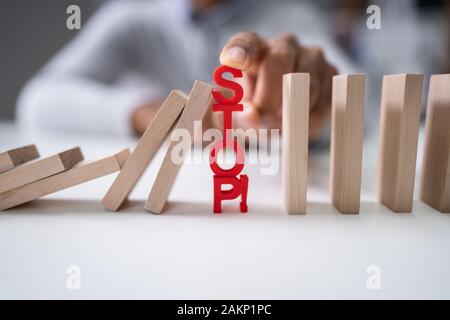 Businessman Stopping the Domino Effect from Small Wooden Blocks on the ...