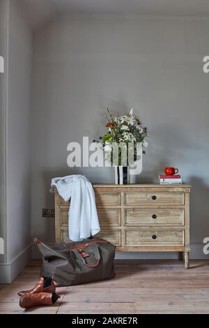 Corner of a bedroom with cushions, a chest of drawers in dark color and ...