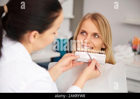 Dentist choosing color of filling from palette. Back view of male ...