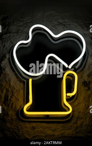 Big glass of frothy dark beer wearing blue cap isolated over blue neon ...