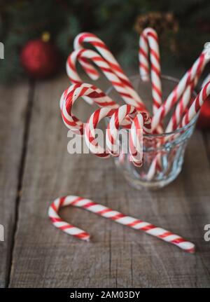 Cup with sweet candy canes and Christmas decor on wooden background ...
