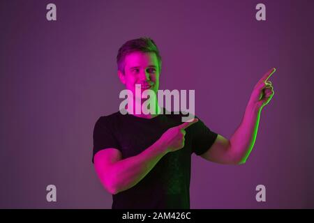 Caucasian man's portrait on purple blue studio background in ...