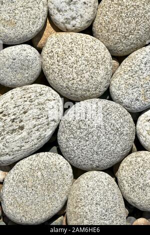 Round flat stones are stacked in a pyramid on a pebble sea beach. In ...
