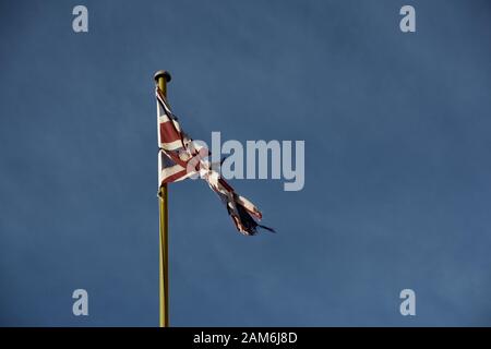 a tattered or battered union flag or union jack flying against a cloudy ...