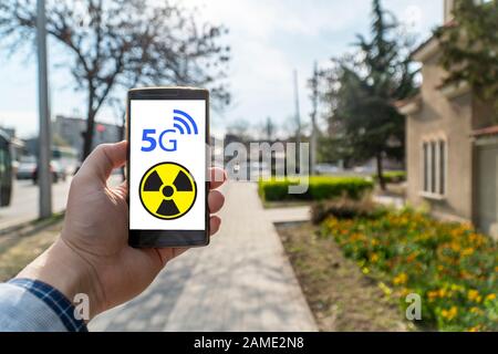 5g network danger on the street. Man holding smartphone with 5g and ...