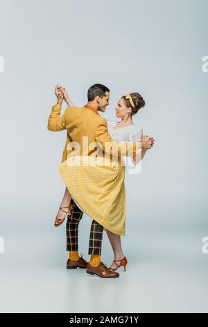 elegant dancers holding hands while dancing boogie-woogie on grey ...