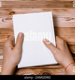 Men's hands holding closed book with blank cover on light background ...