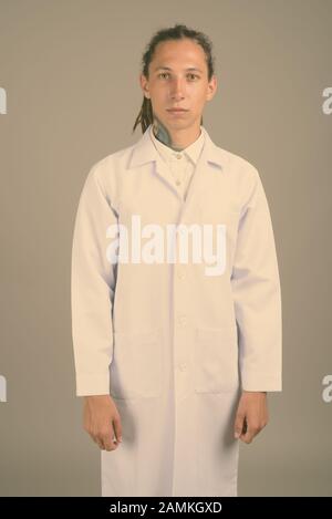 Young man doctor with dreadlocks against gray background Stock Photo ...