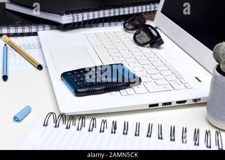 Office desk in busy office with pens computer and note pads White ...