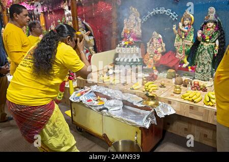 A Hindu priest makes an offering of a coconut to the deities as is a ...