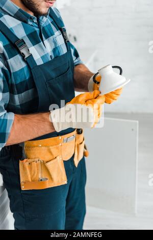 cropped view of man holding funnel with plastic objects on white ...