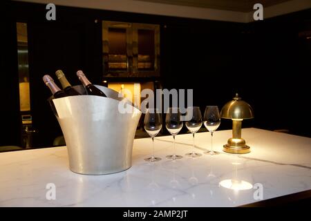 Bucket of champagne and glasses on a marble counter in a warmly lit ...