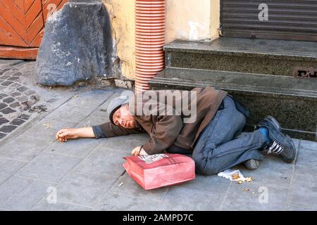 poor drunk man lying near trashcan in city street Stock Photo - Alamy